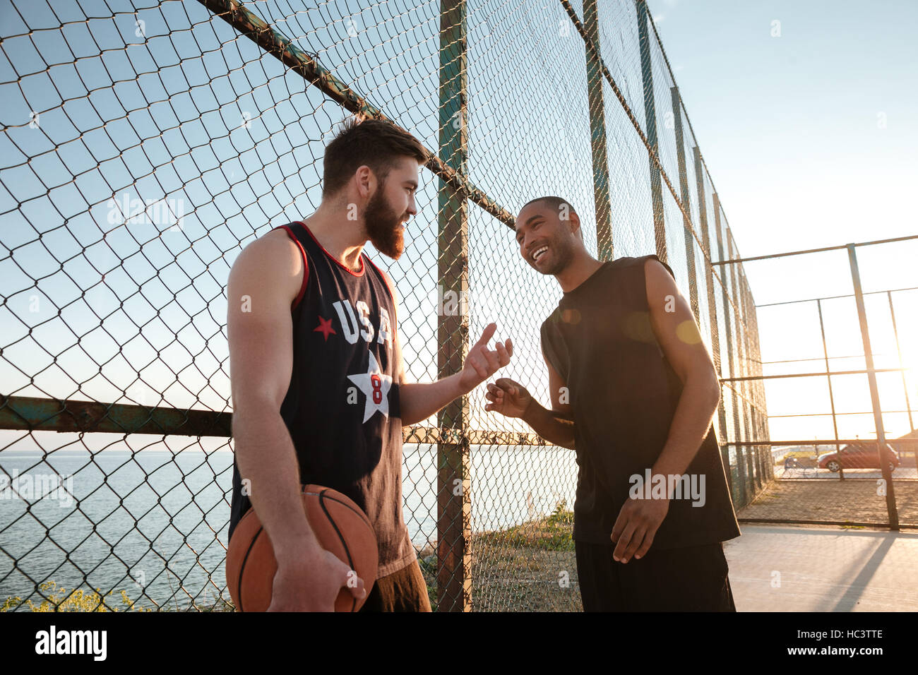 Two happy smiling basketball players talking while standing at the ...