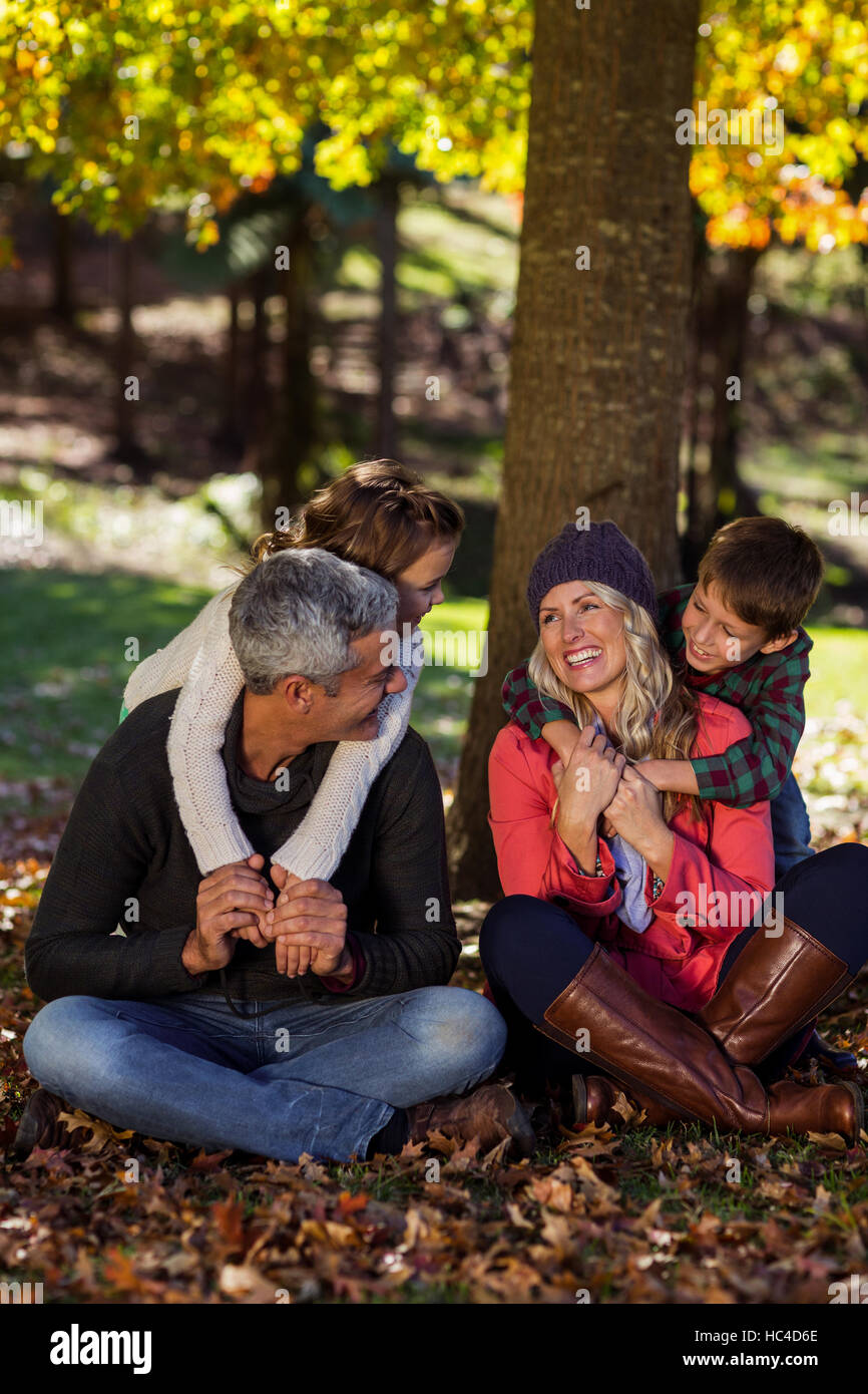 Happy family sitting under tree at park Stock Photo - Alamy
