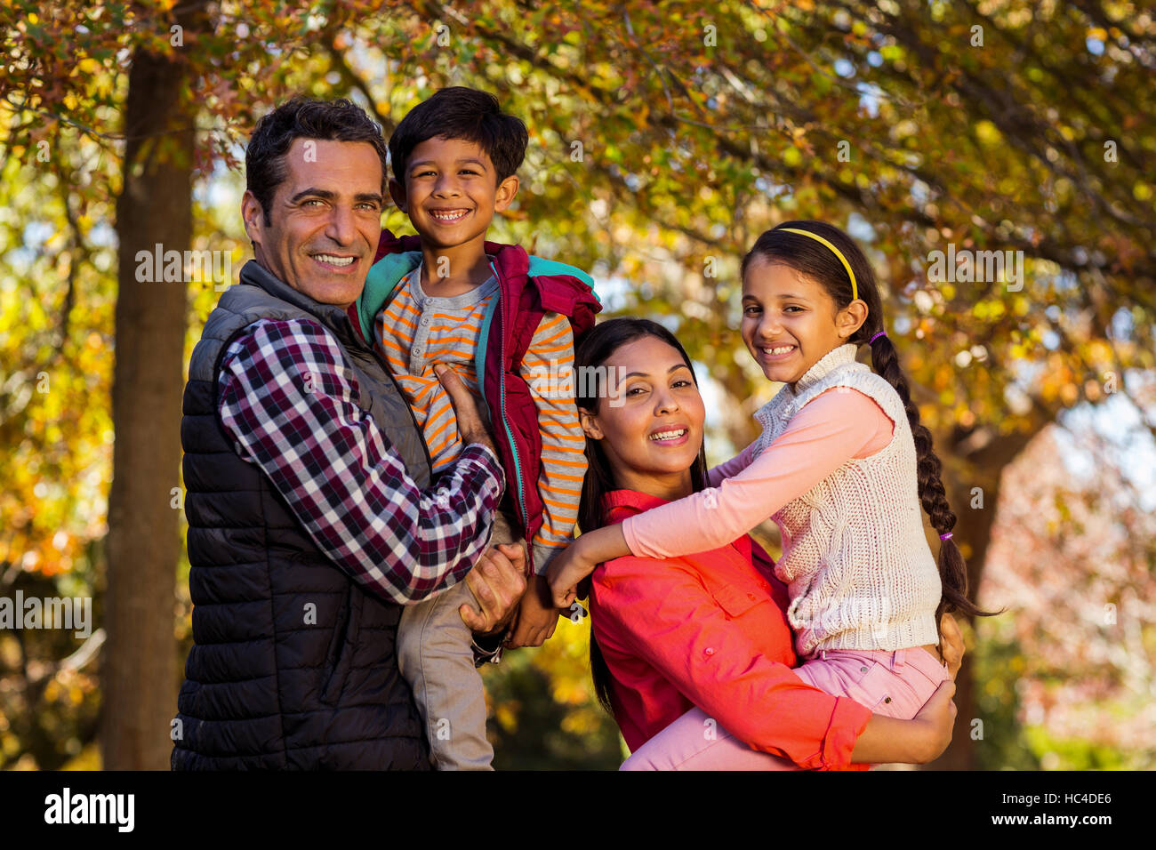 Parents carrying children while standing at park Stock Photo - Alamy