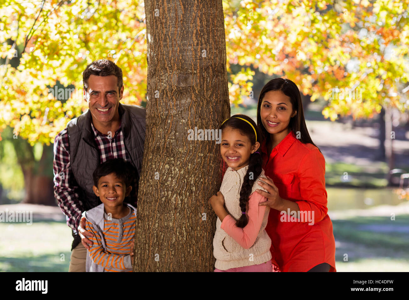 Portrait of smiling family standing by tree Stock Photo - Alamy
