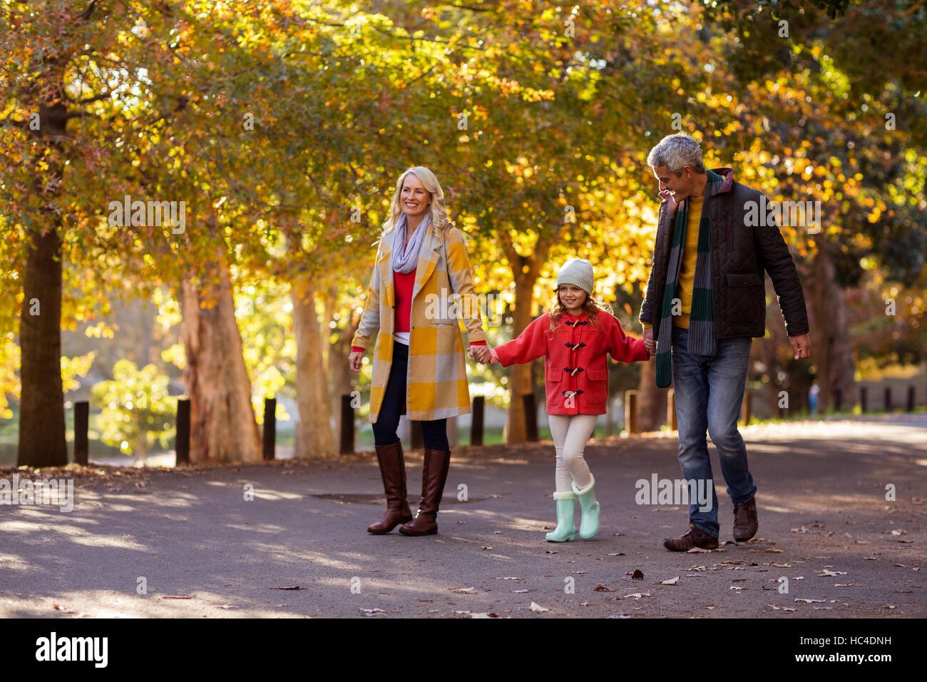 Girl walking with parents on road Stock Photo - Alamy