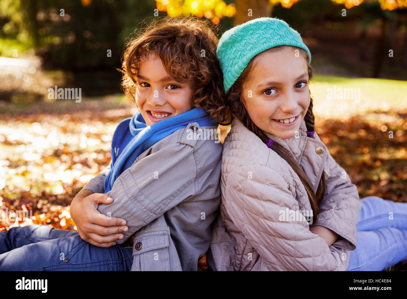Portrait of smiling siblings with arms crossed in park Stock Photo - Alamy