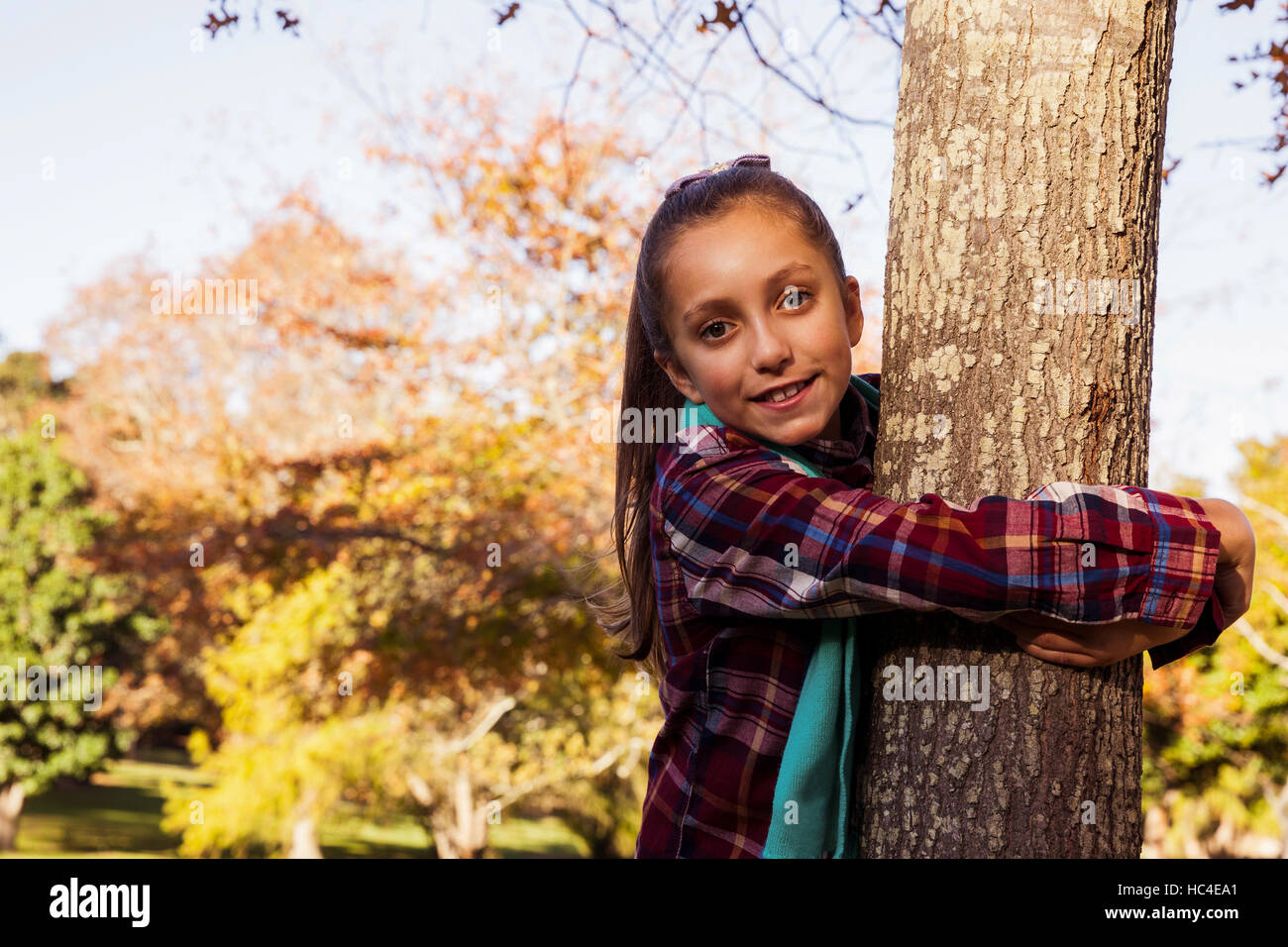 Portrait of smiling girl hugging tree Stock Photo - Alamy