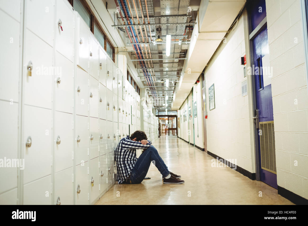 Depressed student sitting in locker room Stock Photo - Alamy