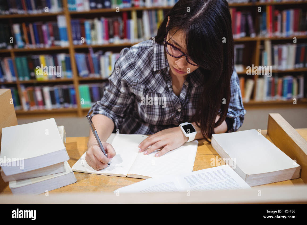 Female student writing notes in library Stock Photo - Alamy