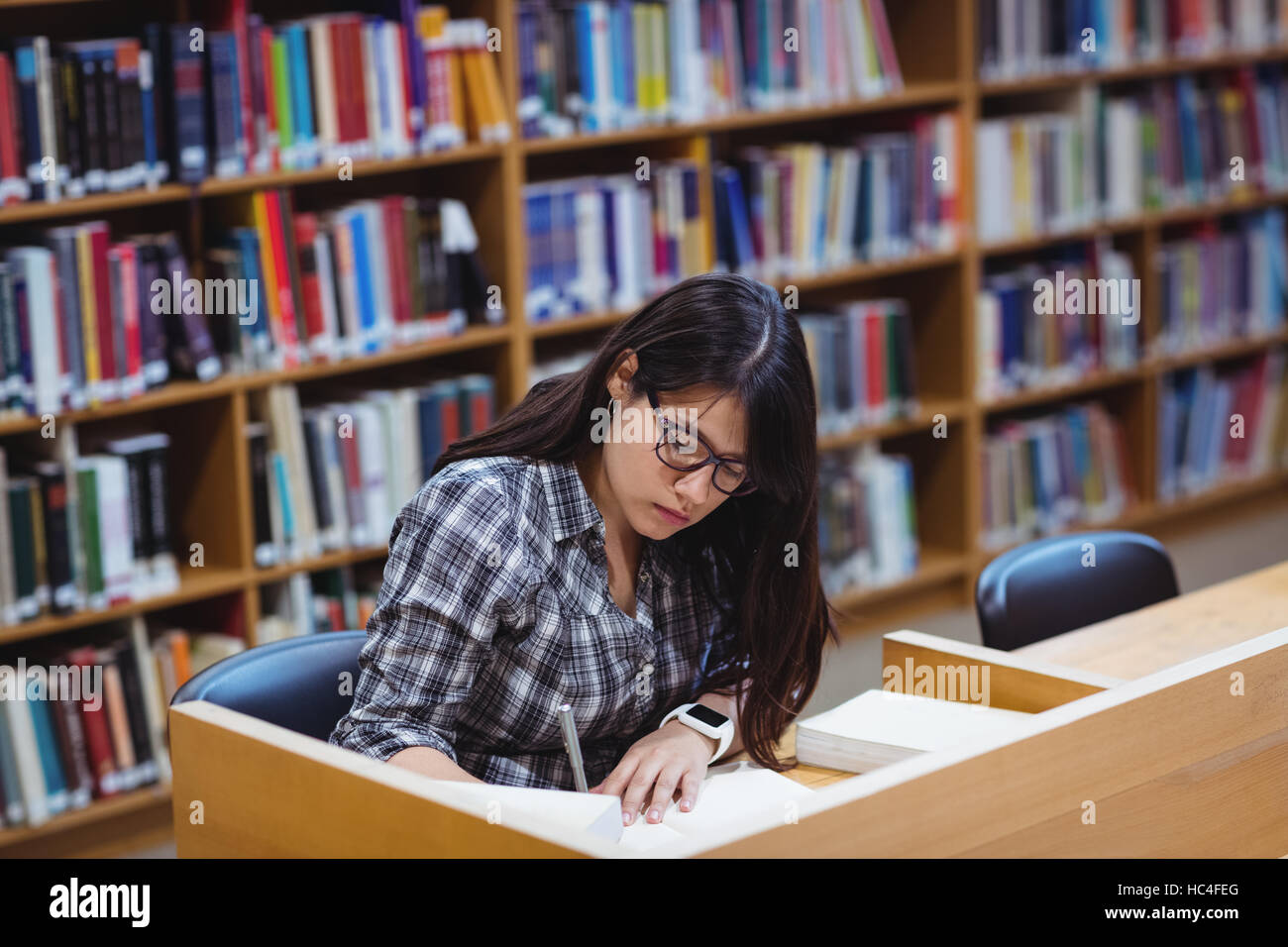 Female student writing notes in library Stock Photo - Alamy
