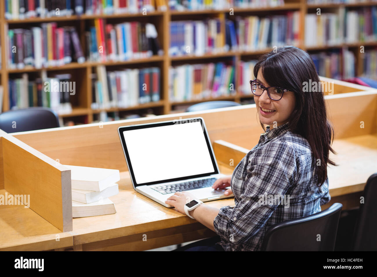 Smiling Female student using laptop in library Stock Photo - Alamy