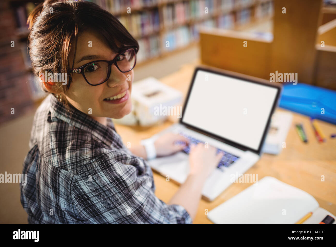 Smiling Female student using laptop in library Stock Photo - Alamy