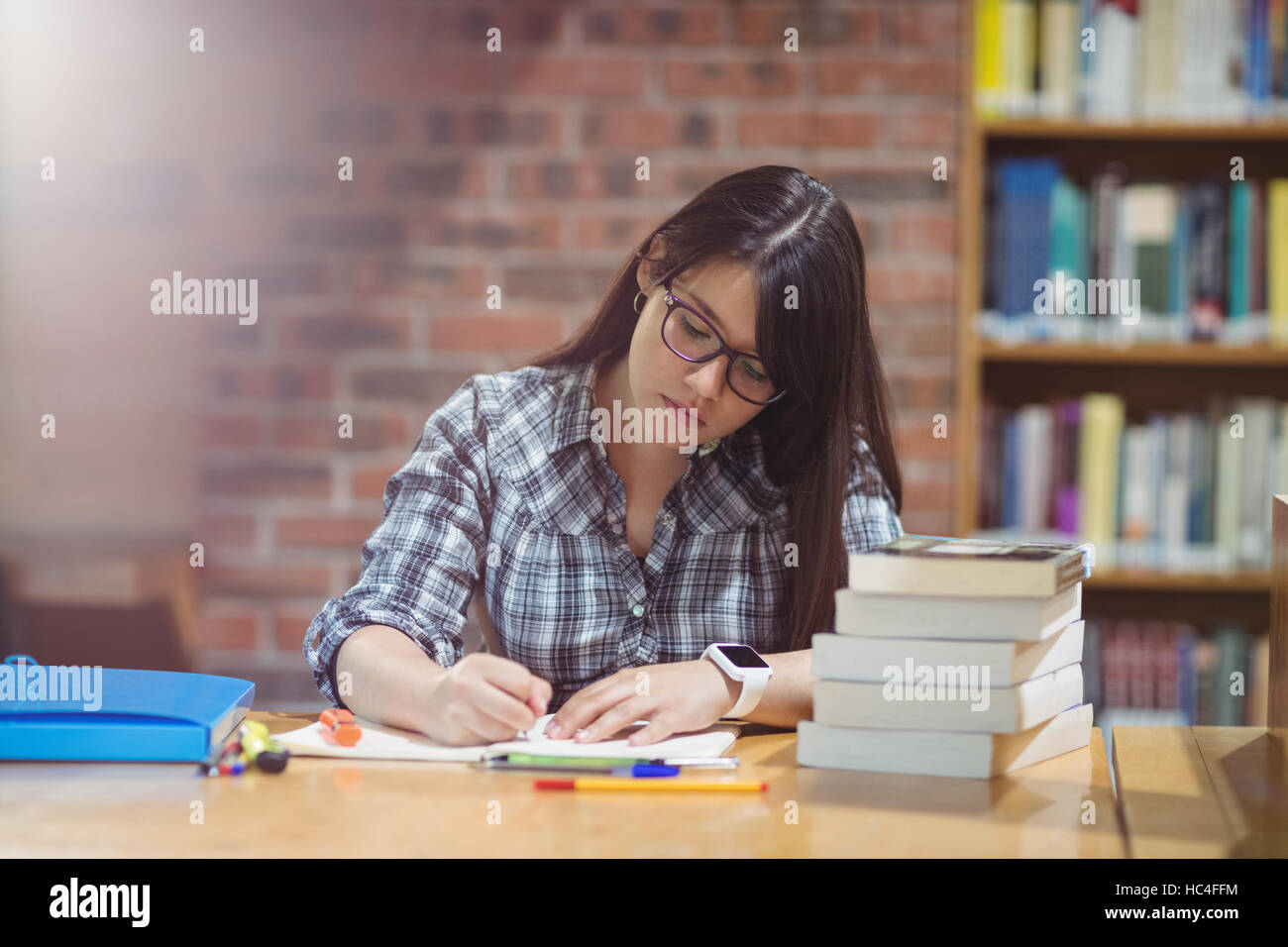 Female student writing notes in library Stock Photo - Alamy