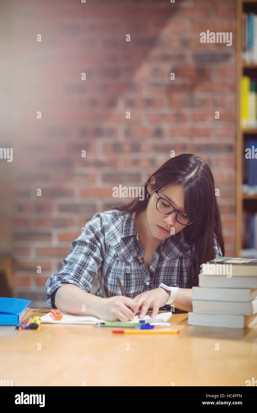 Female student writing notes in library Stock Photo - Alamy