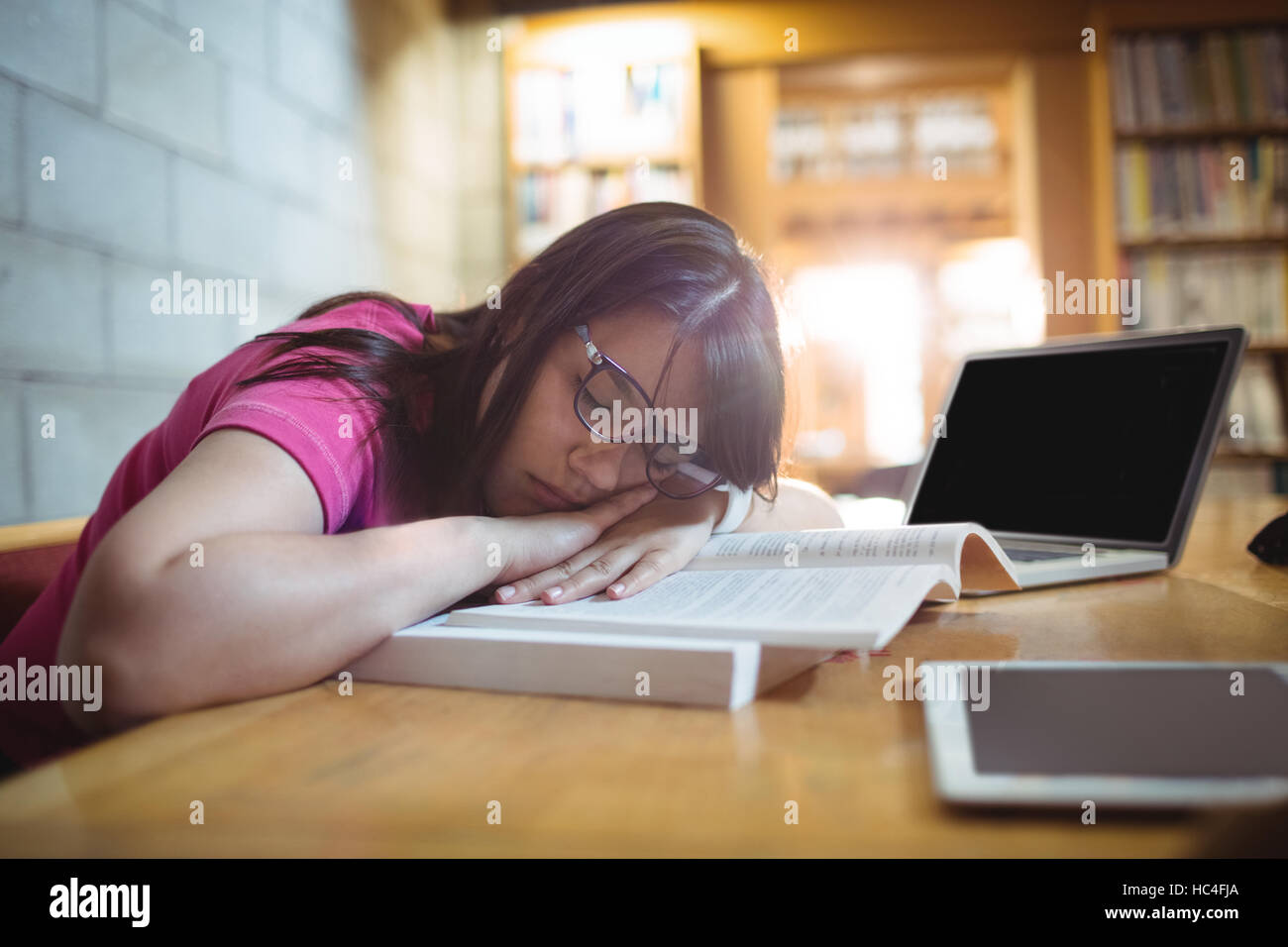 Female student napping on book in library Stock Photo - Alamy