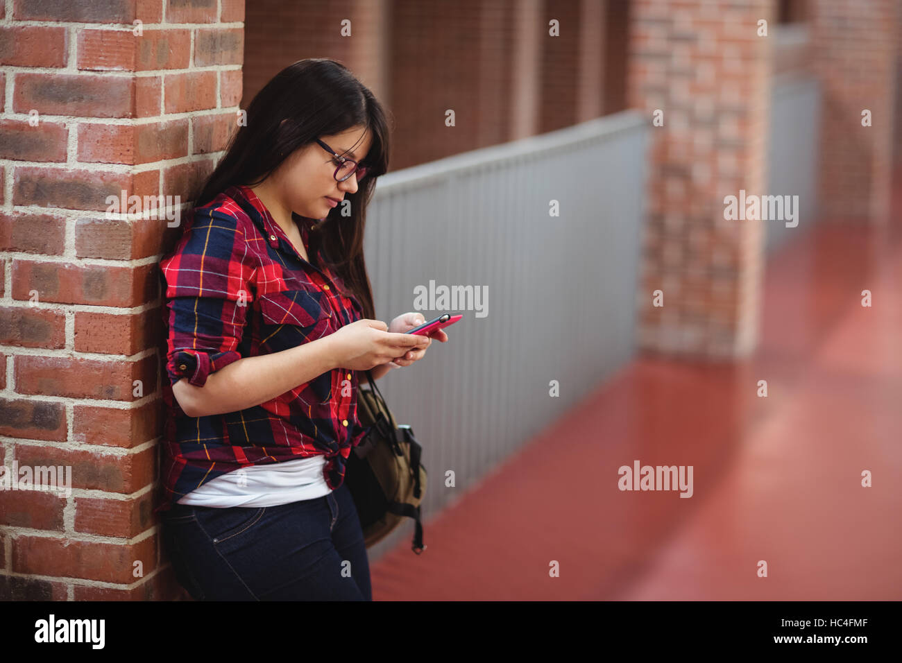Female student using mobile phone in corridor Stock Photo - Alamy