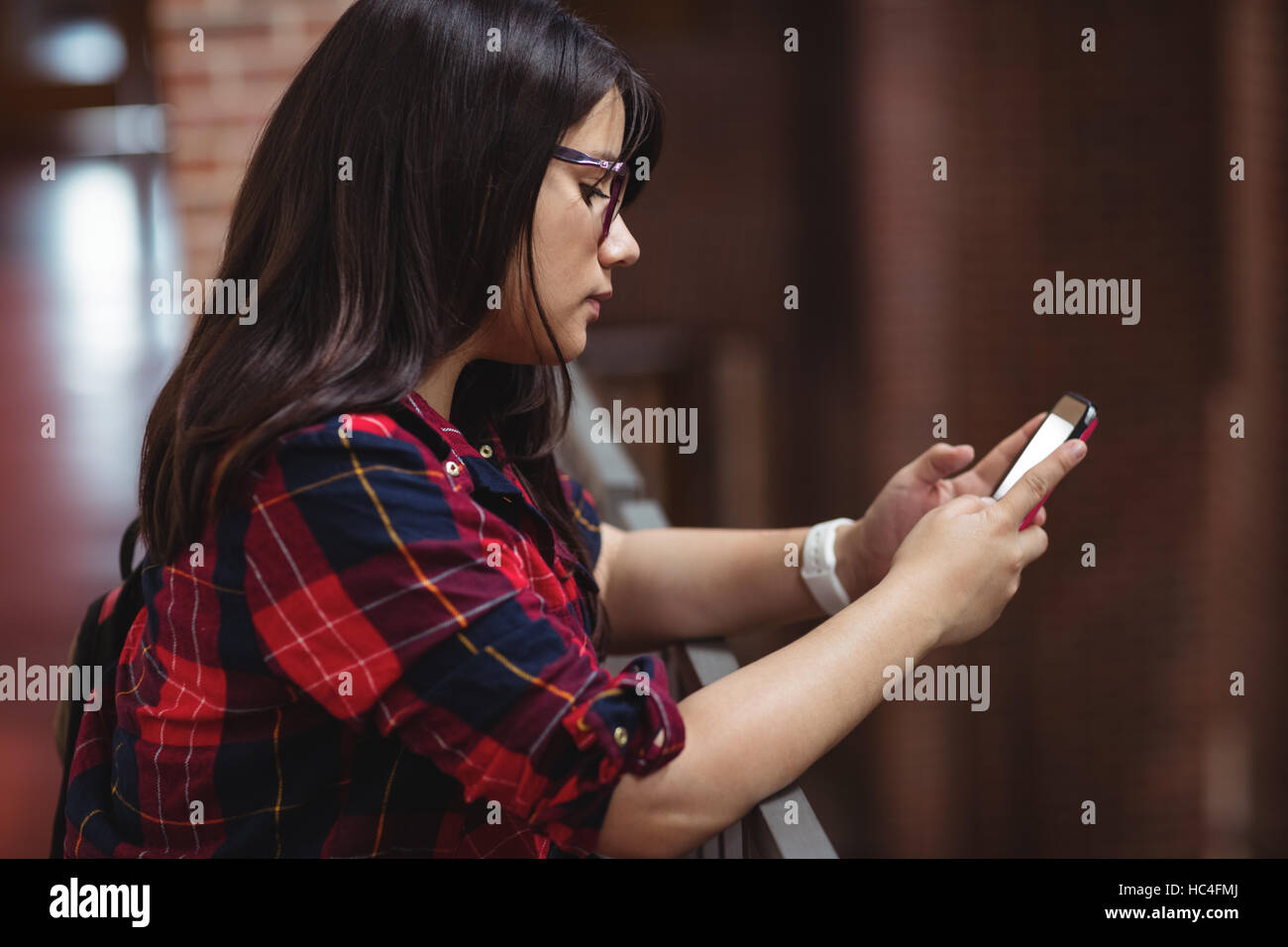 Female student using mobile phone in corridor Stock Photo - Alamy