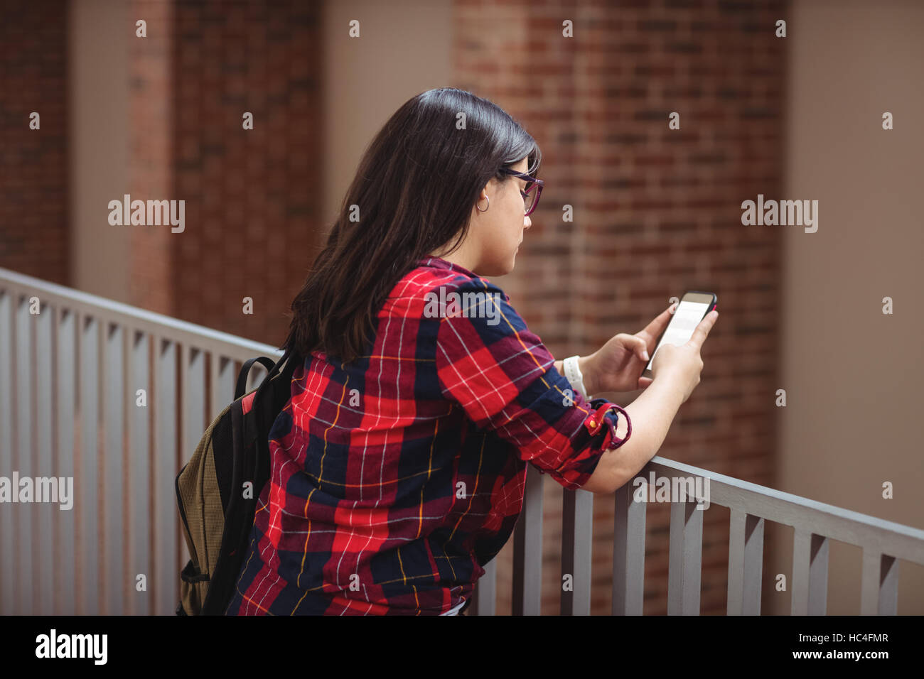 Female student using mobile phone in corridor Stock Photo - Alamy