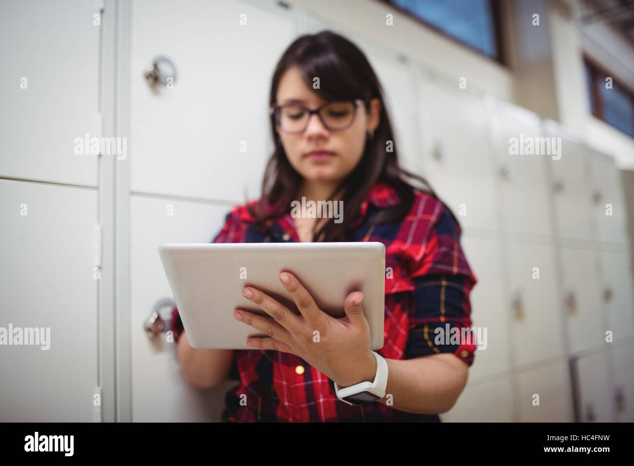 Female student using digital tablet in locker room Stock Photo - Alamy