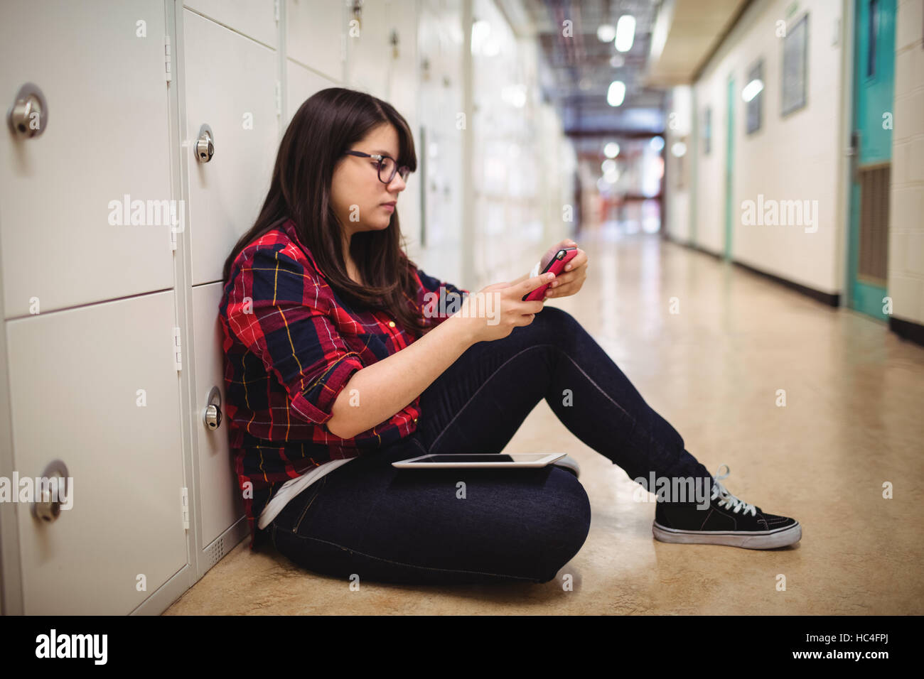 Female student using mobile phone in locker room Stock Photo - Alamy