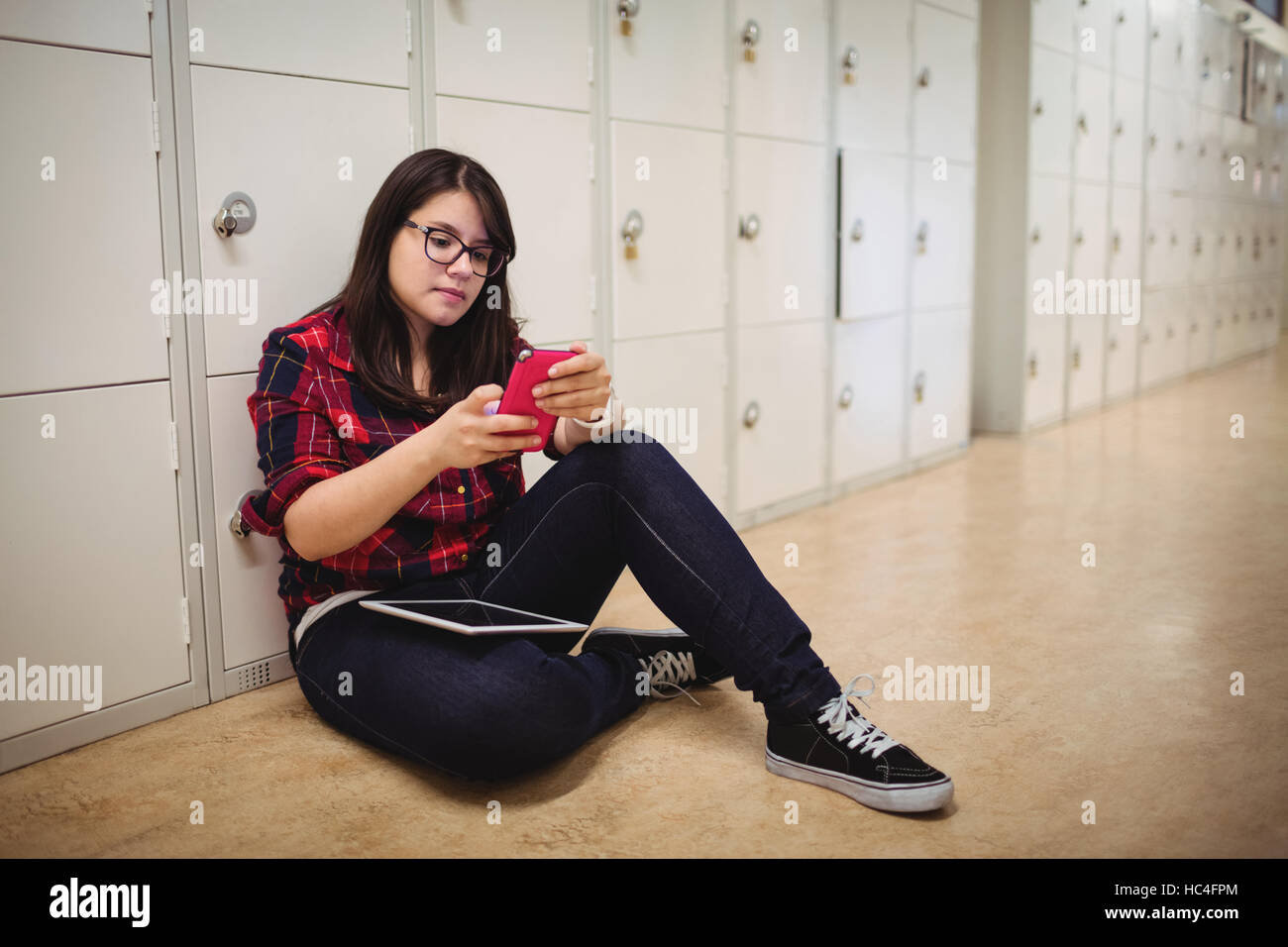 Female student using mobile phone in locker room Stock Photo - Alamy