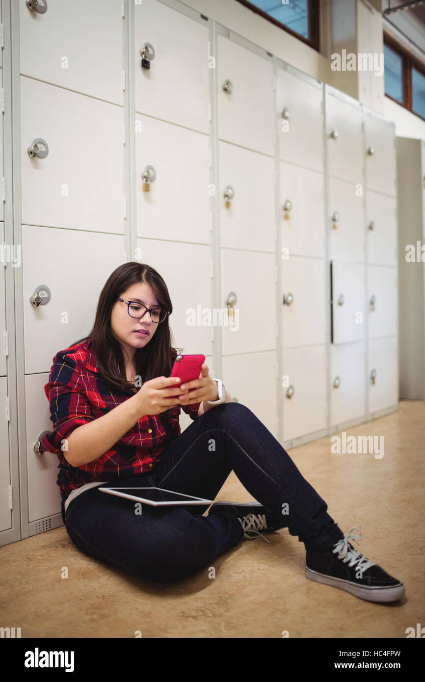 Female student using mobile phone in locker room Stock Photo - Alamy