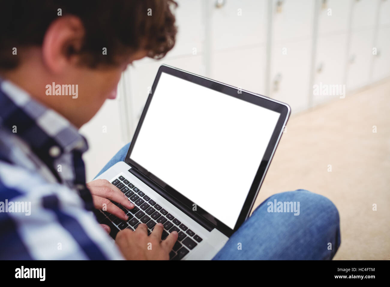 Student using laptop in locker room Stock Photo - Alamy