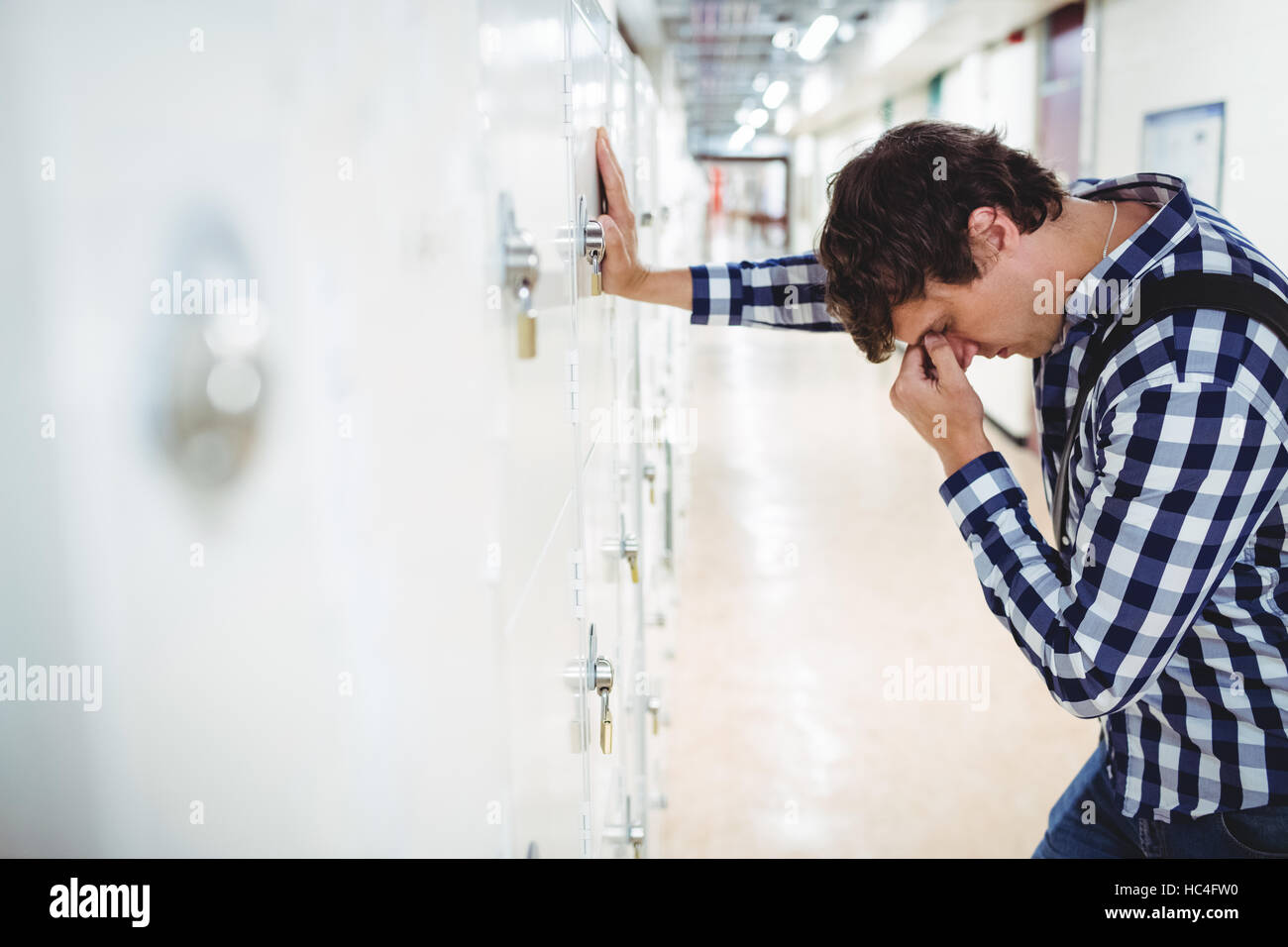 Sad student leaning on locker Stock Photo - Alamy