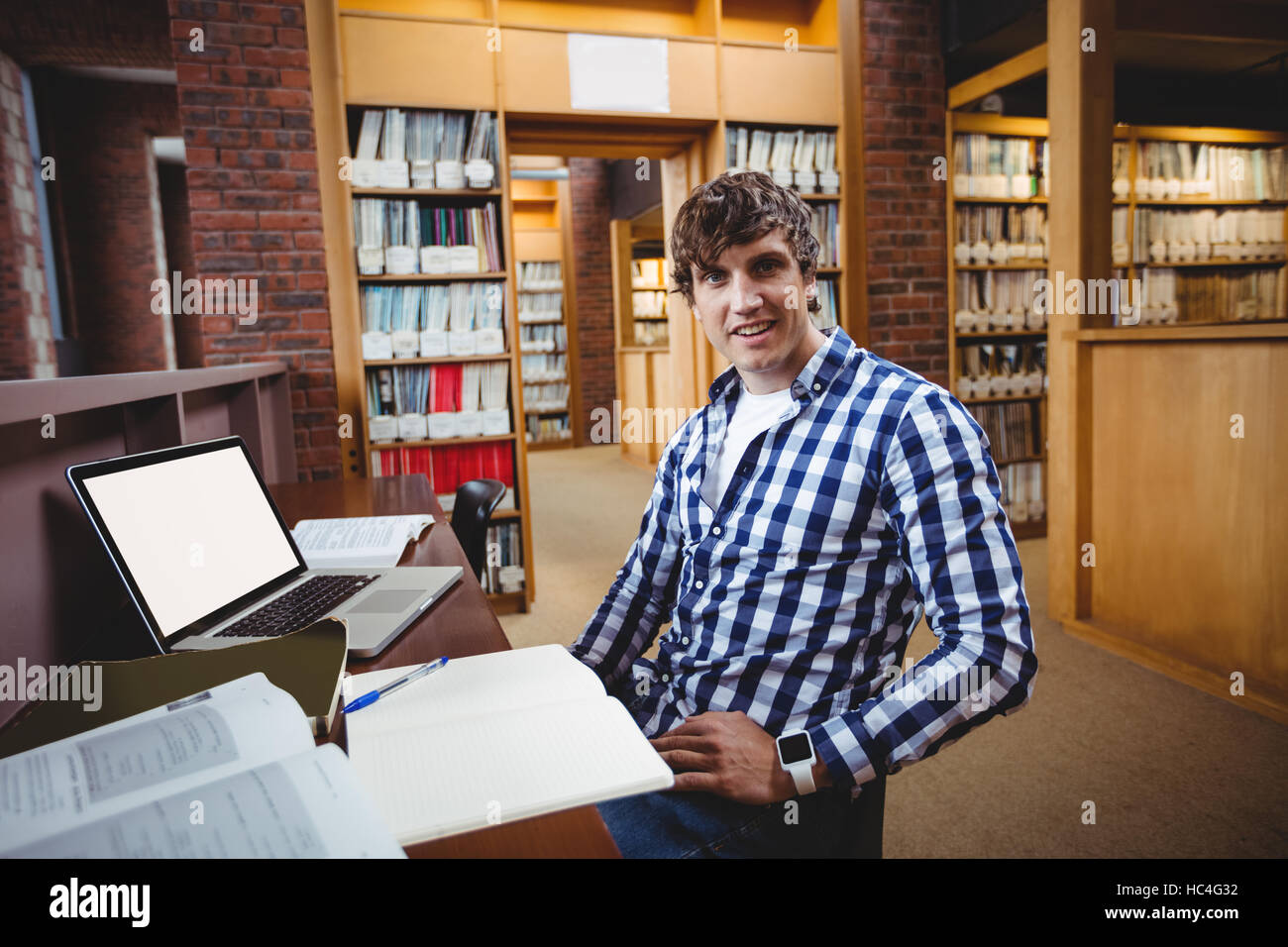 Smiling student sitting in library Stock Photo - Alamy