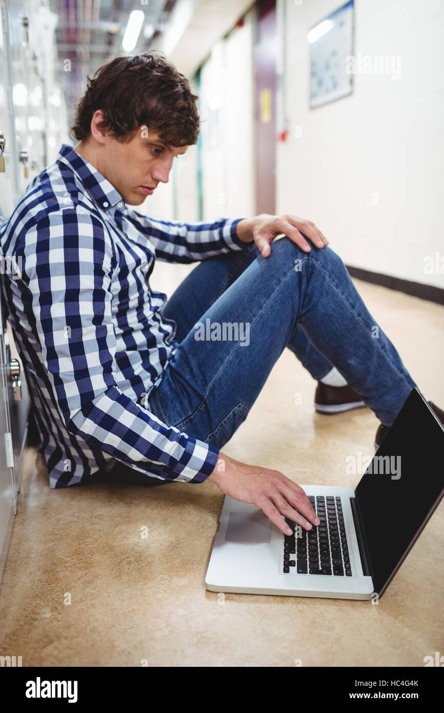 Student using laptop in locker room Stock Photo - Alamy