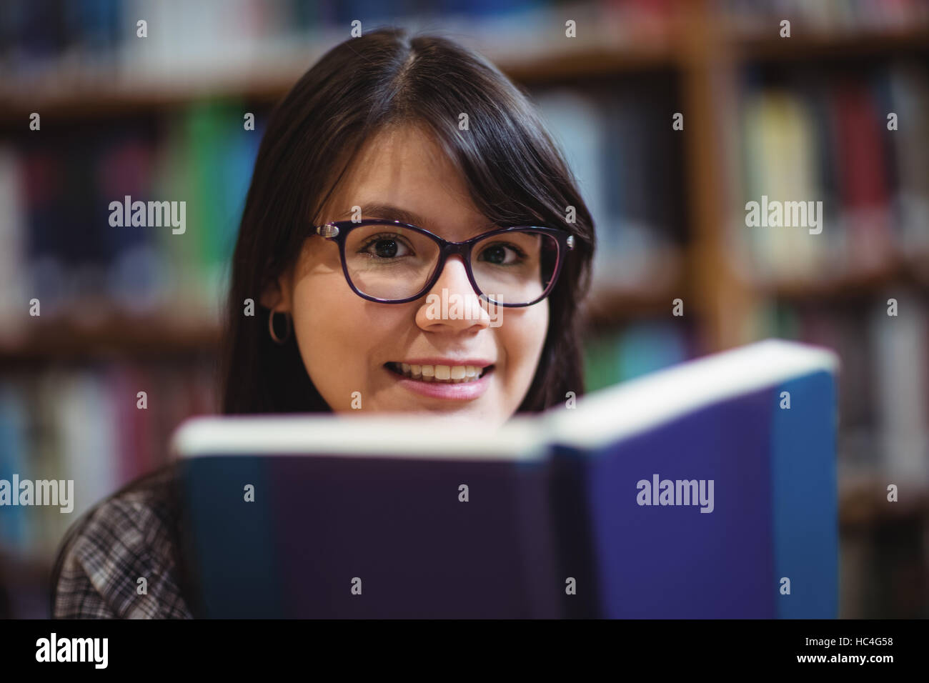 Female student holding book in college library Stock Photo - Alamy