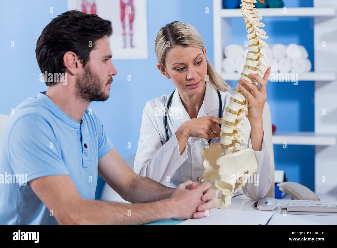 Physiotherapist explaining the spine model to patient Stock Photo - Alamy