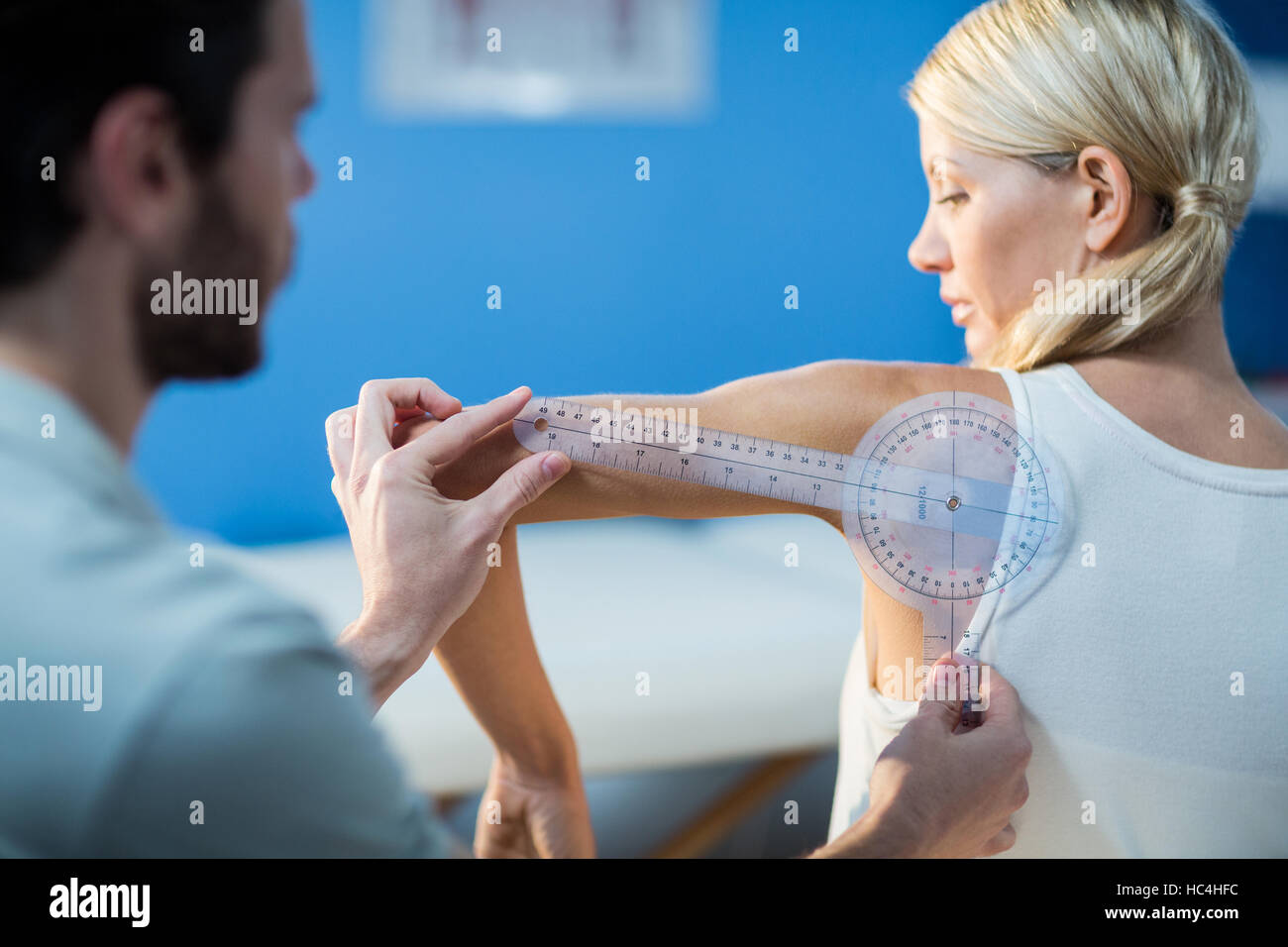 Male therapist measuring female patient shoulder with goniometer Stock ...