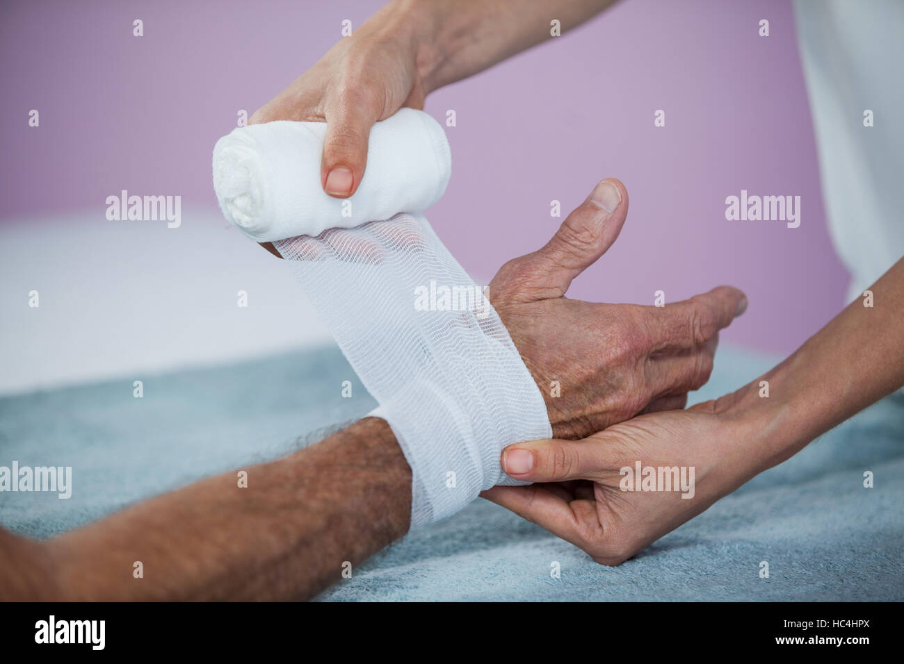 Physiotherapist putting bandage on injured hand of patient Stock Photo ...