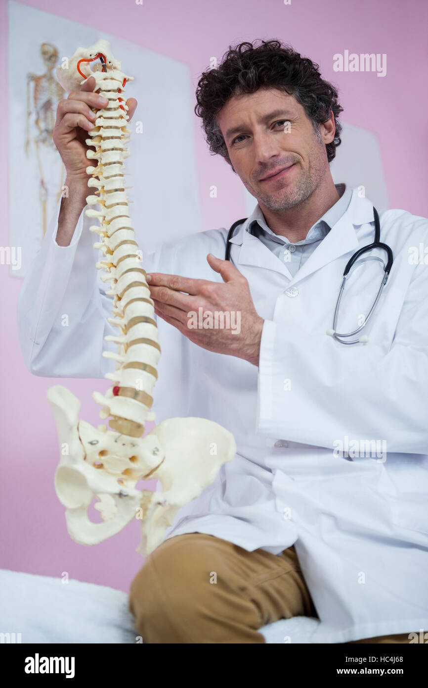 Portrait of physiotherapist sitting with spine model Stock Photo - Alamy