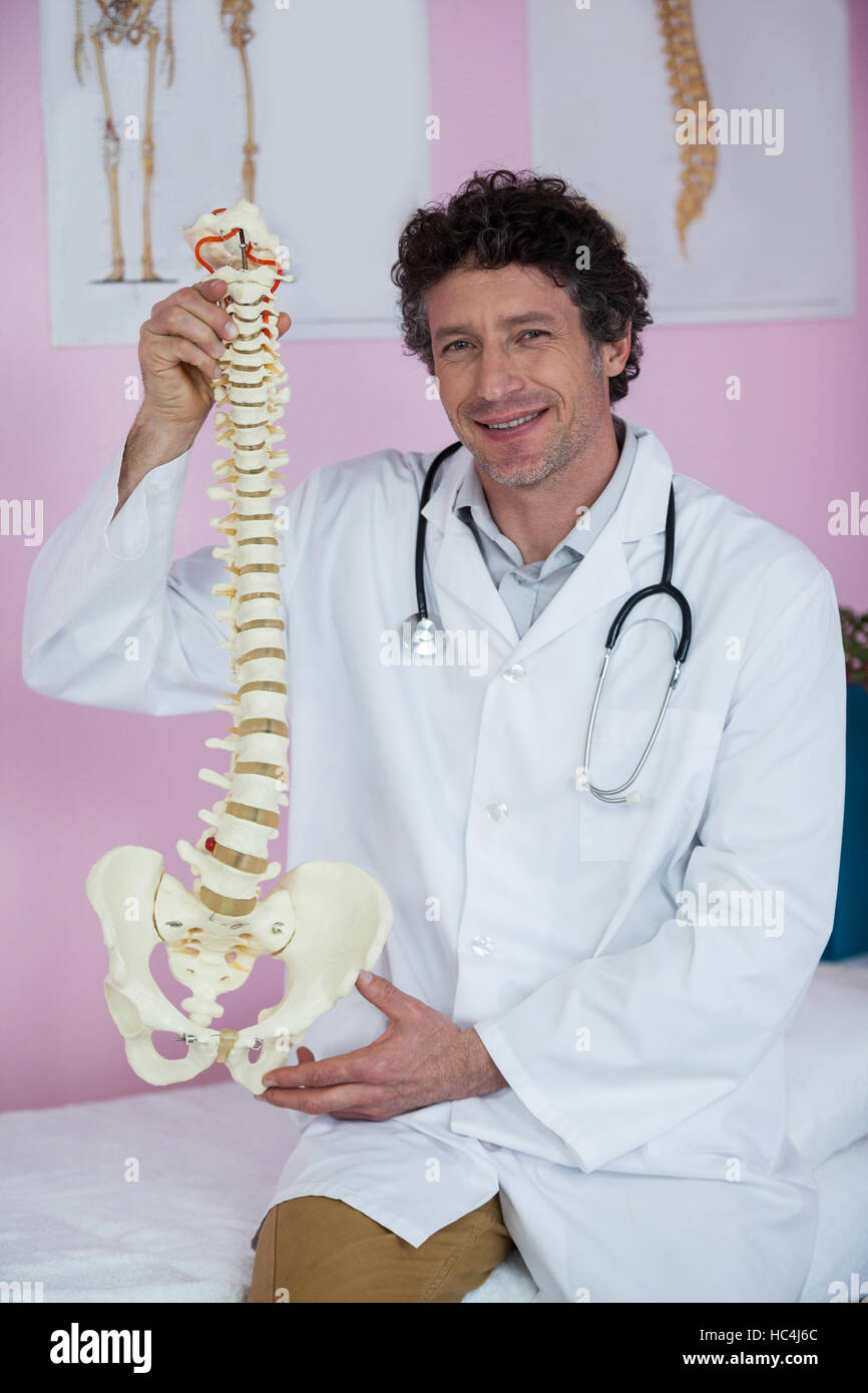 Portrait of physiotherapist sitting with spine model Stock Photo - Alamy