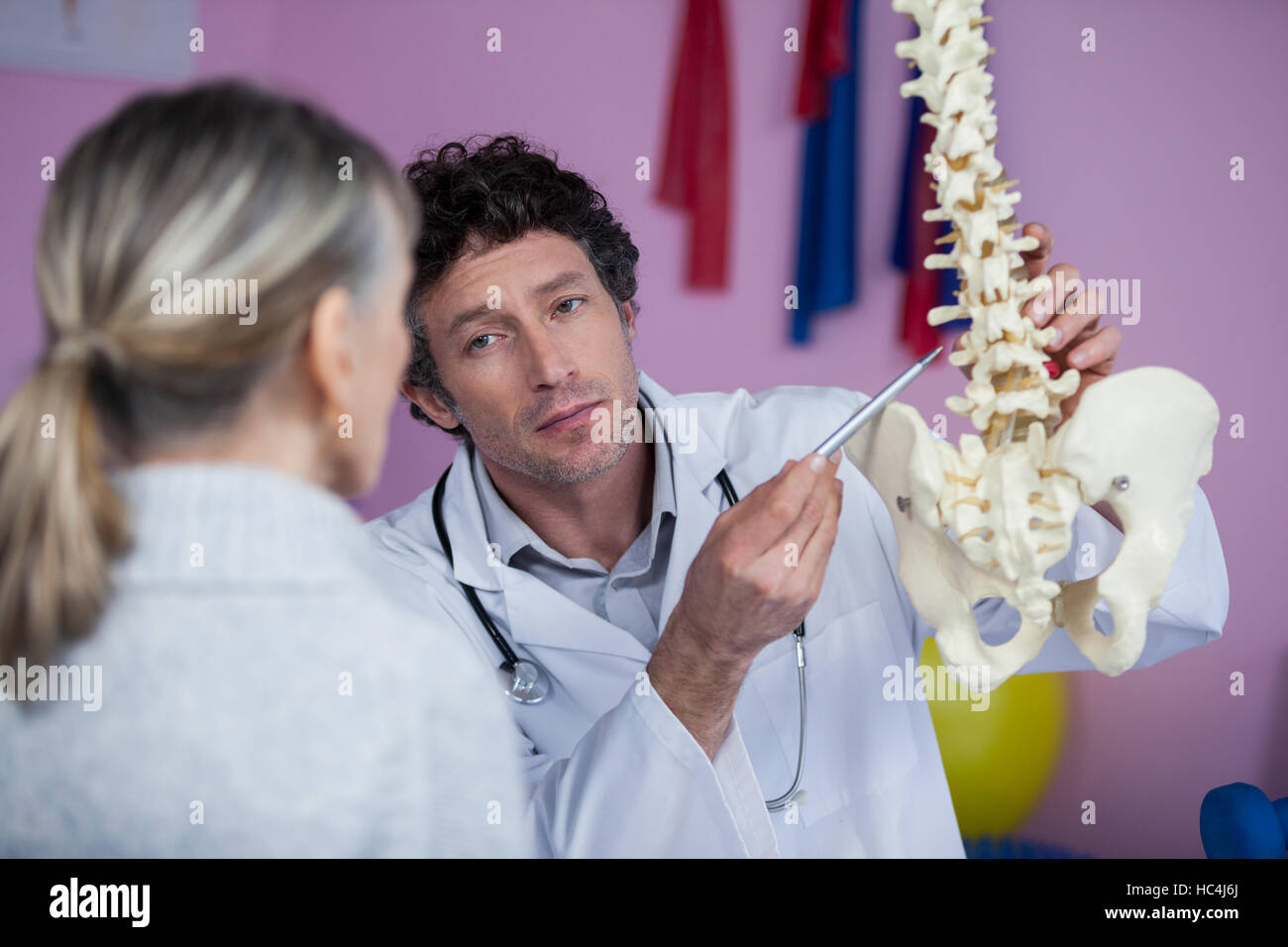 Physiotherapist explaining the spine model to patient Stock Photo - Alamy