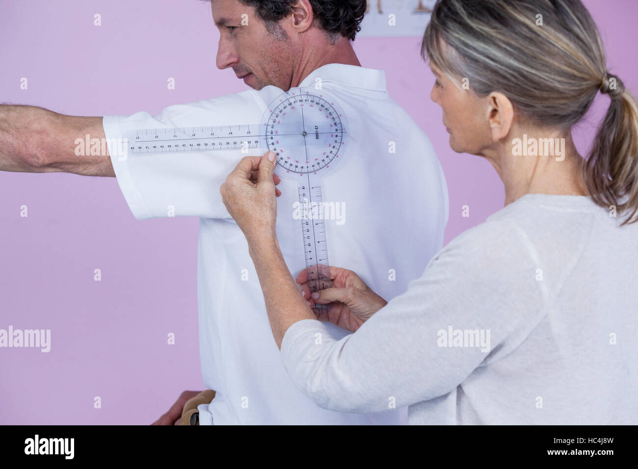 Physiotherapist measuring male patients back with medical ruler Stock ...