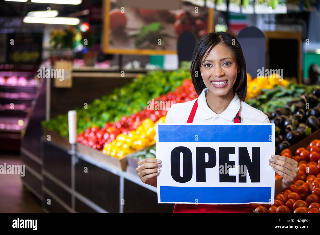 Smiling female staff holding open signboard Stock Photo - Alamy