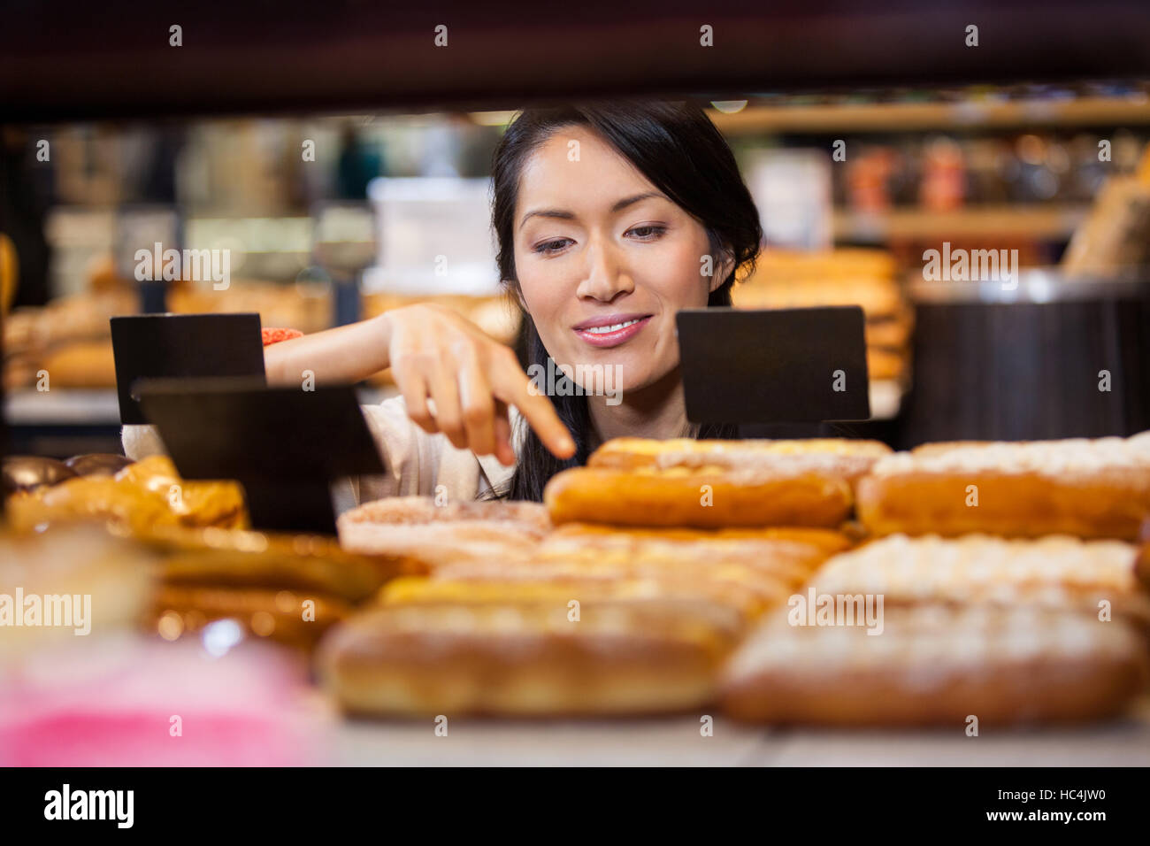 Woman selecting baguettes from bread counter Stock Photo - Alamy