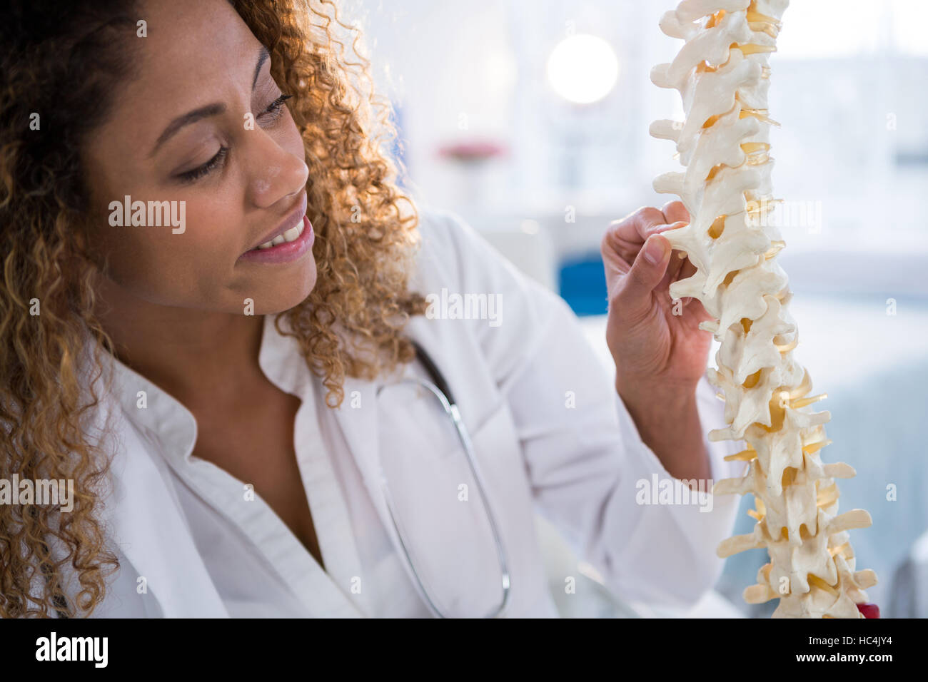 Smiling physiotherapist looking at spine model Stock Photo - Alamy