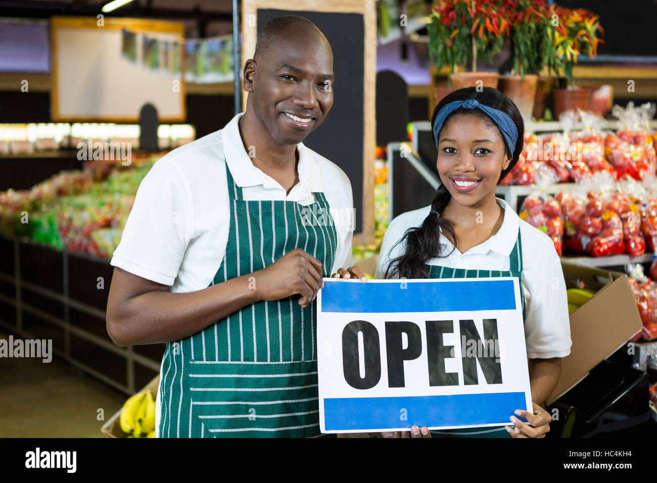 Smiling staffs holding open sign board in organic section Stock Photo ...