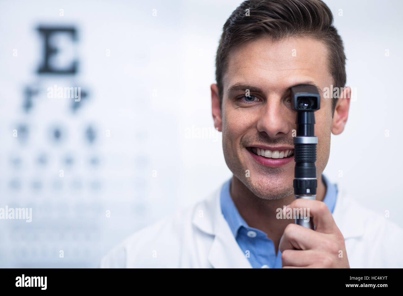Smiling optometrist looking through ophthalmoscope Stock Photo - Alamy