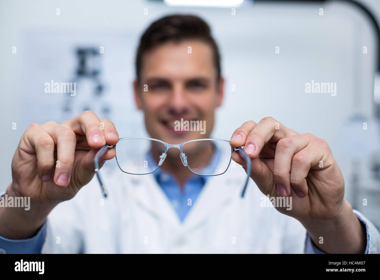 Smiling optometrist holding spectacles Stock Photo - Alamy
