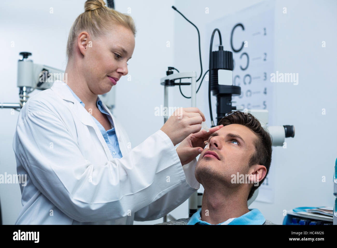 Female optometrist putting eye drop in patient eyes Stock Photo - Alamy