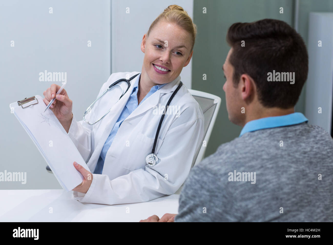 Smiling female doctor explaining patient on clipboard Stock Photo - Alamy