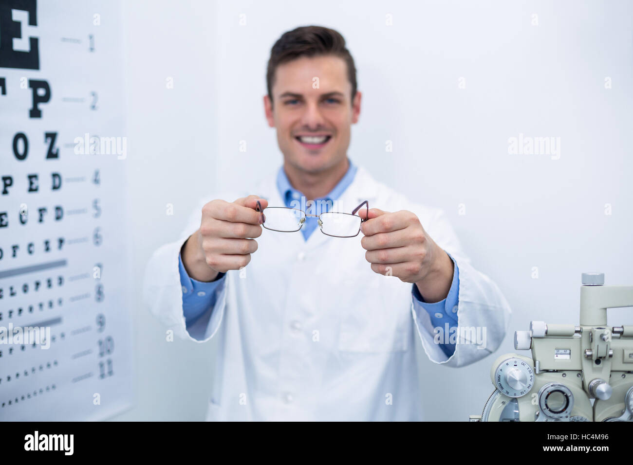 Smiling optometrist holding spectacles Stock Photo - Alamy