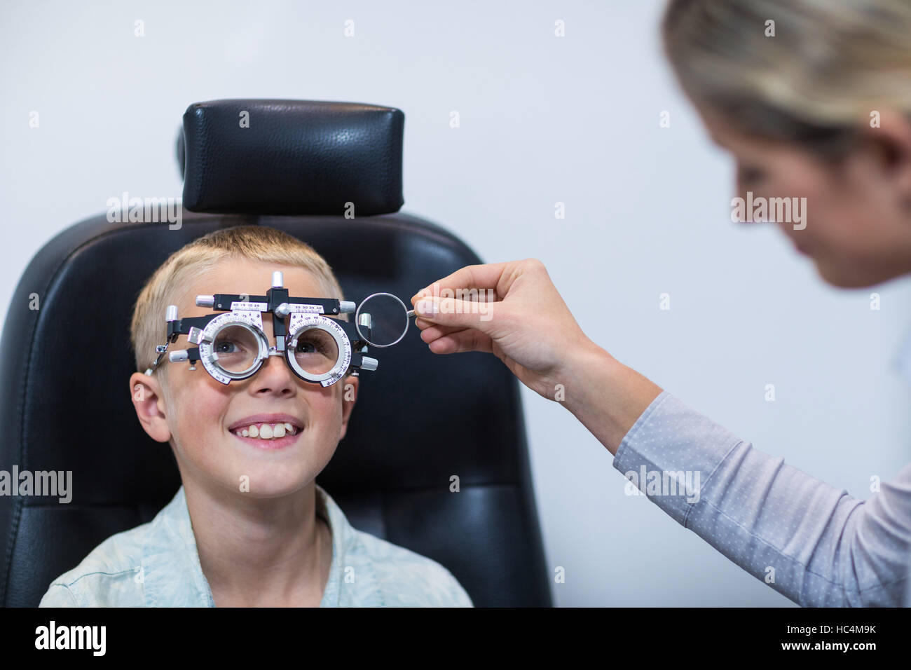 Female optometrist examining young patient with phoropter Stock Photo ...