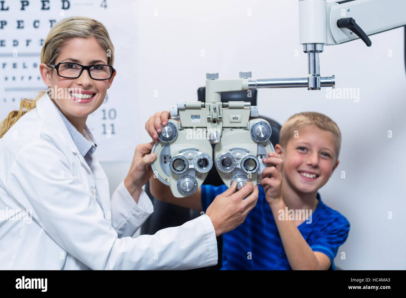 Optometrist and young patient smiling while under going eye test Stock ...