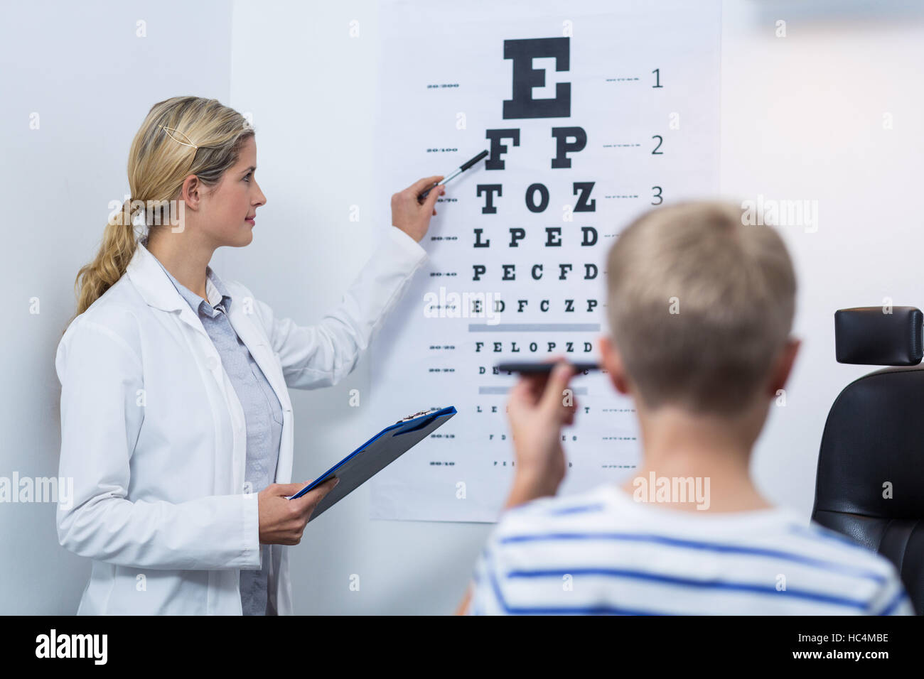 Female optometrist taking eye test of young patient Stock Photo - Alamy