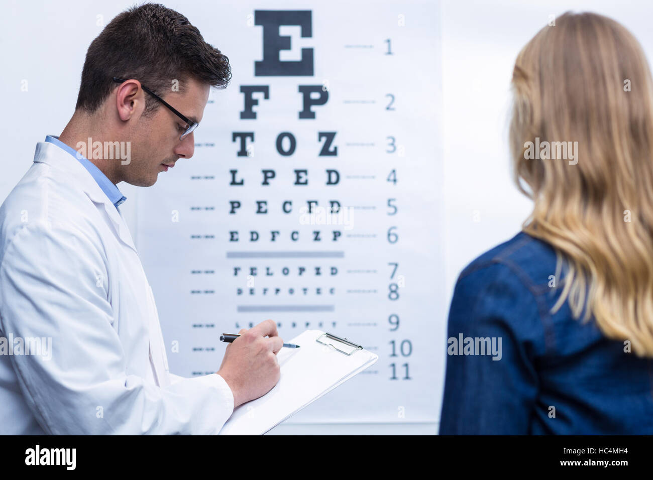 Optometrist writing on clipboard Stock Photo - Alamy