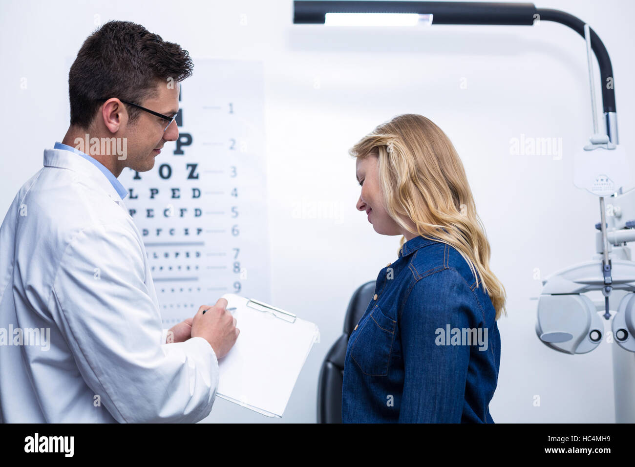 Optometrist discussing eye test report with female patient Stock Photo ...