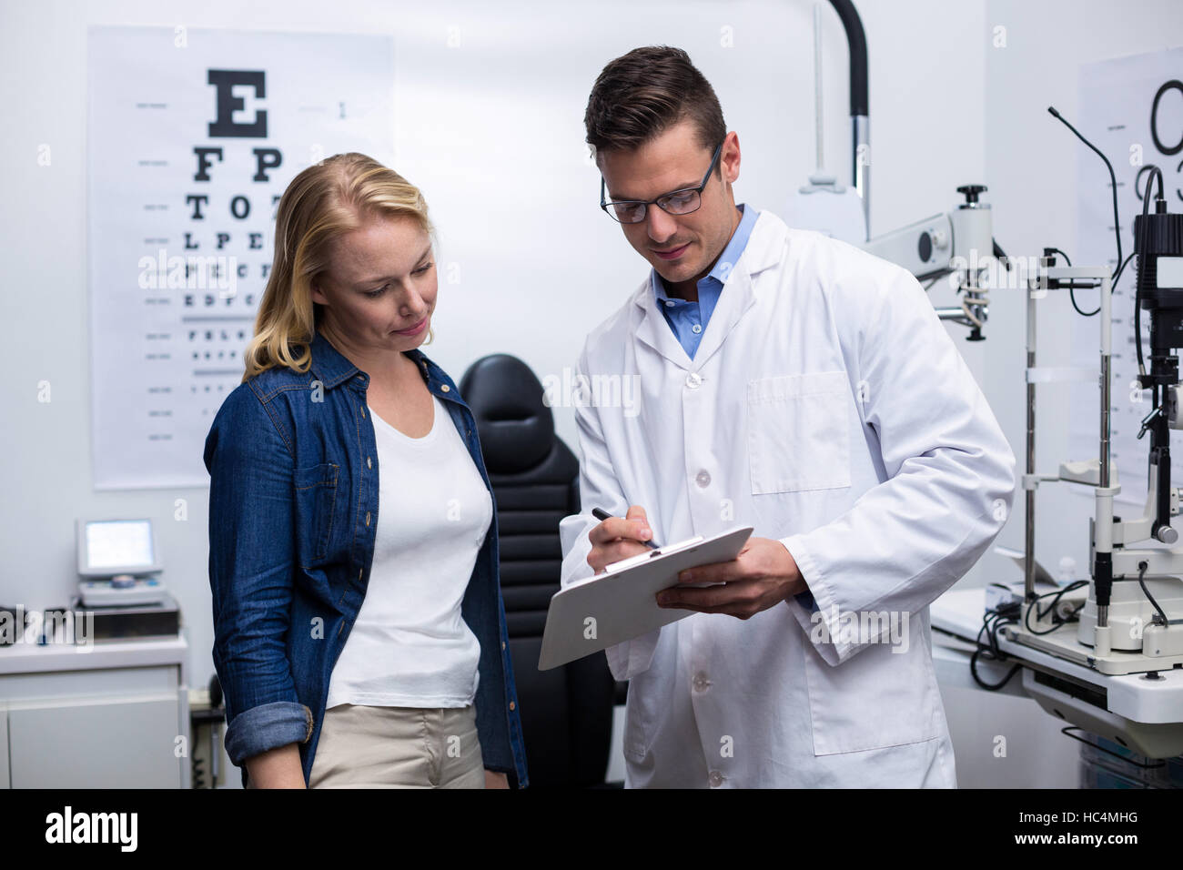 Optometrist discussing eye test report with female patient Stock Photo ...