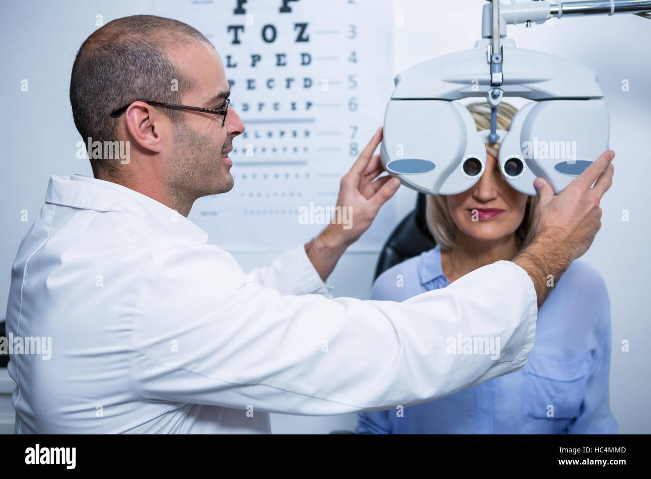 Smiling optometrist examining female patient on phoropter Stock Photo ...